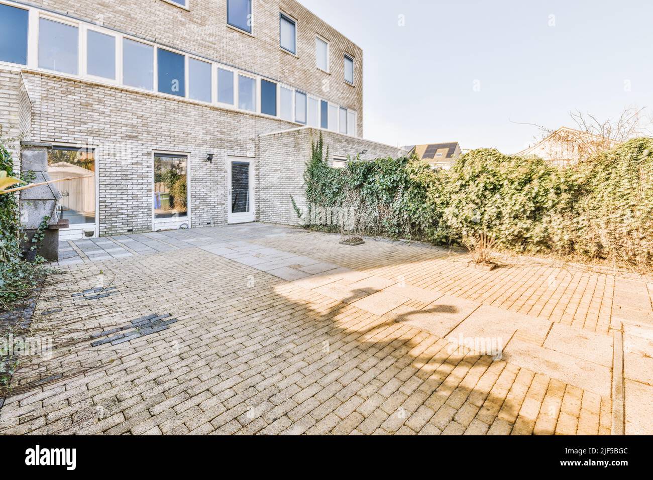 View of a brick building with white-framed windows and a paved yard ...