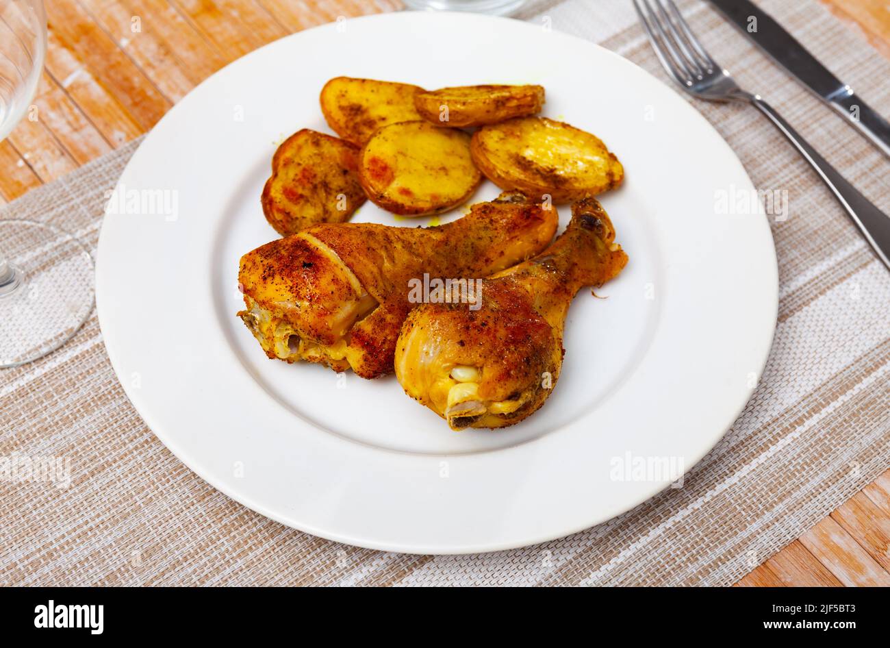 Baked chicken legs with garnish of fried potatoes in skins Stock Photo ...