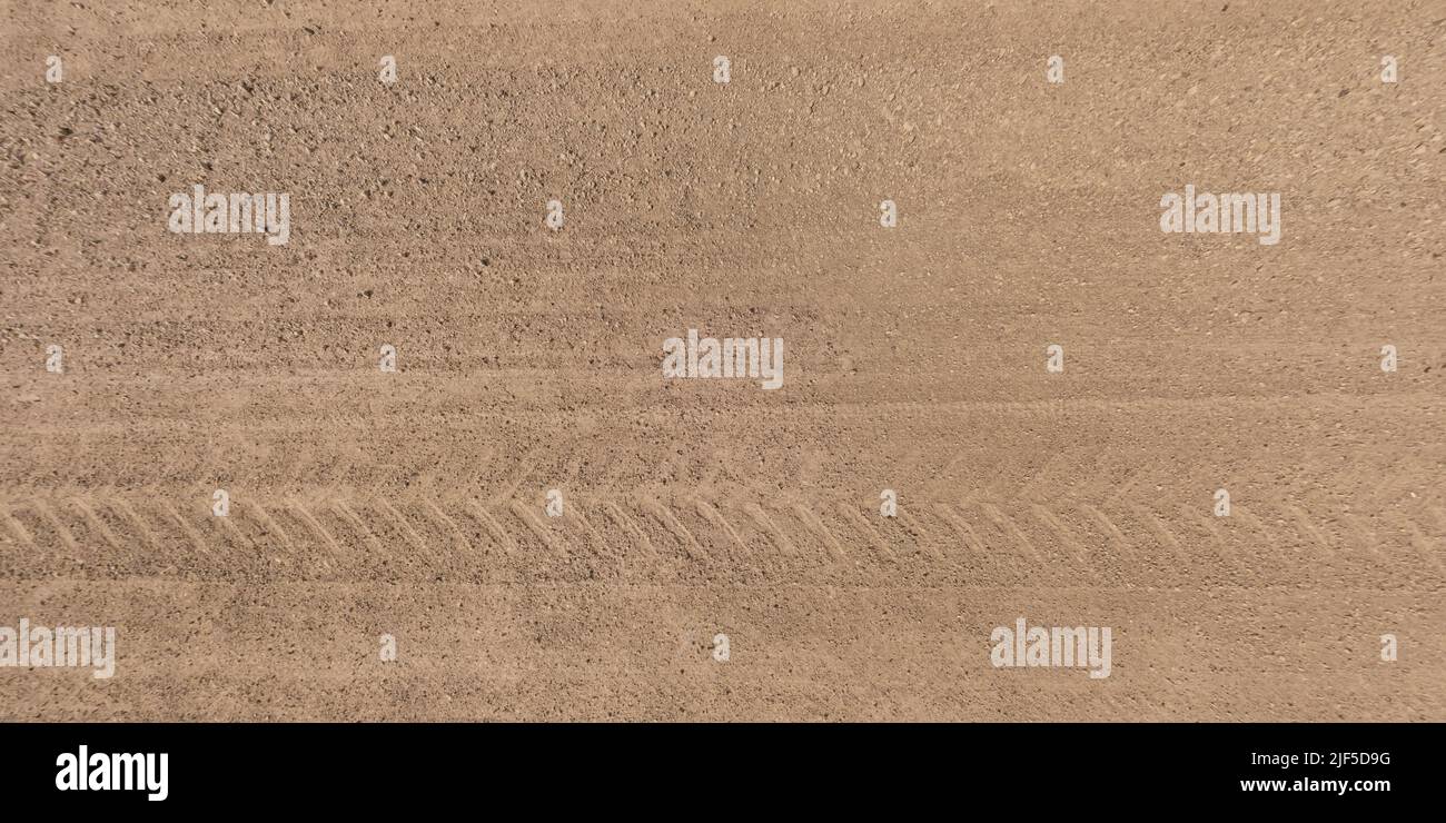 panorama of surface from above of gravel road with car tire tracks ...