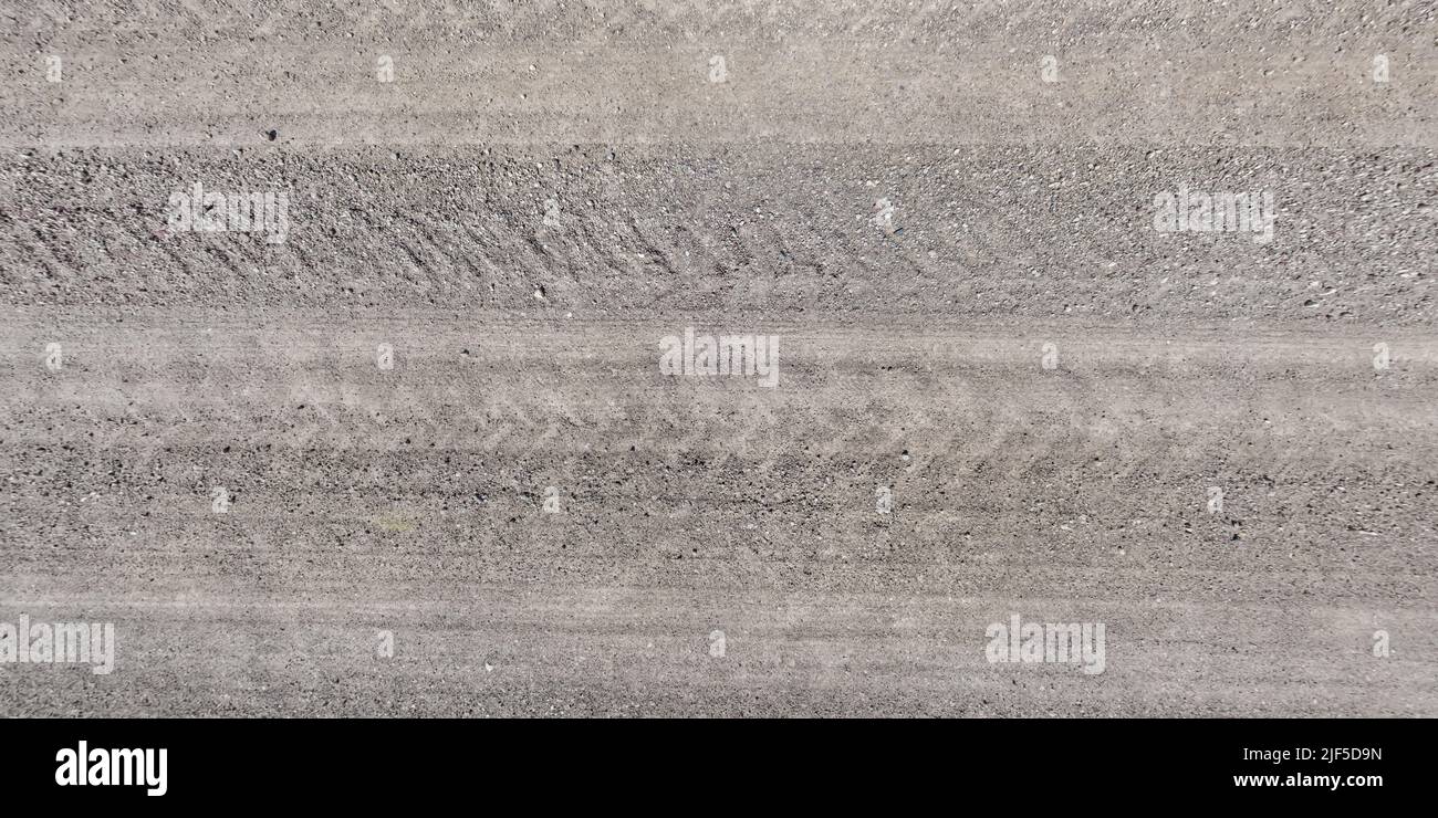 panorama of surface from above of gravel road with car tire tracks ...
