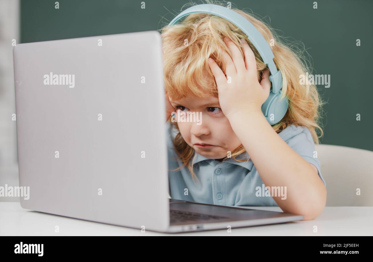 Angry sad school kid working in computer class. Little funny system ...