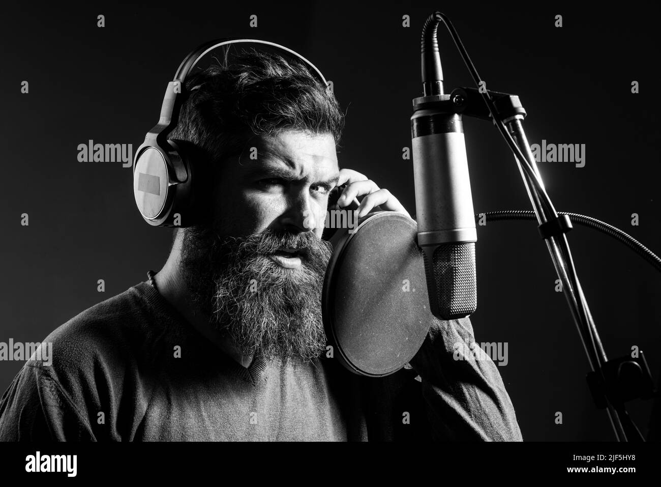 Portrait of singer wearing headphones is performing a song with a ...