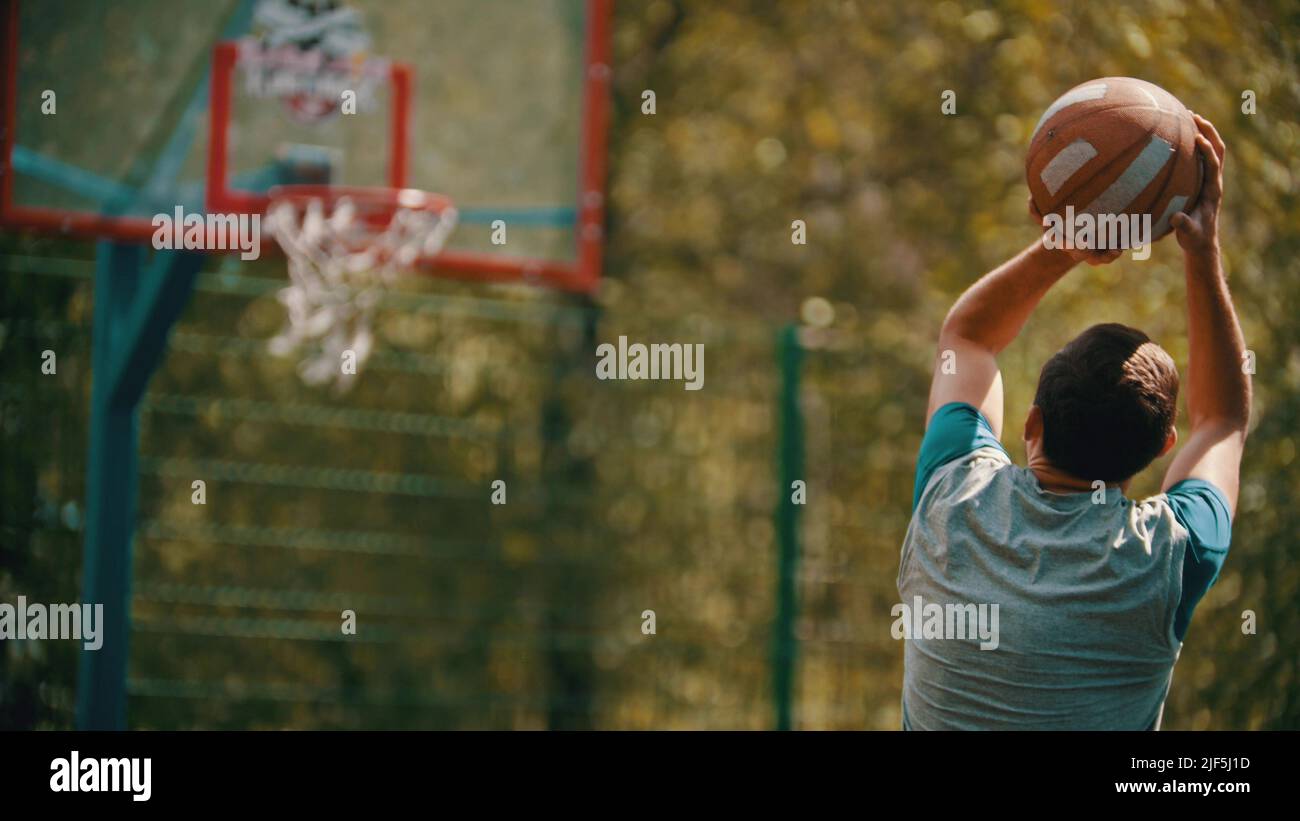 A young man jump and about to throw the ball in the basketball hoop ...