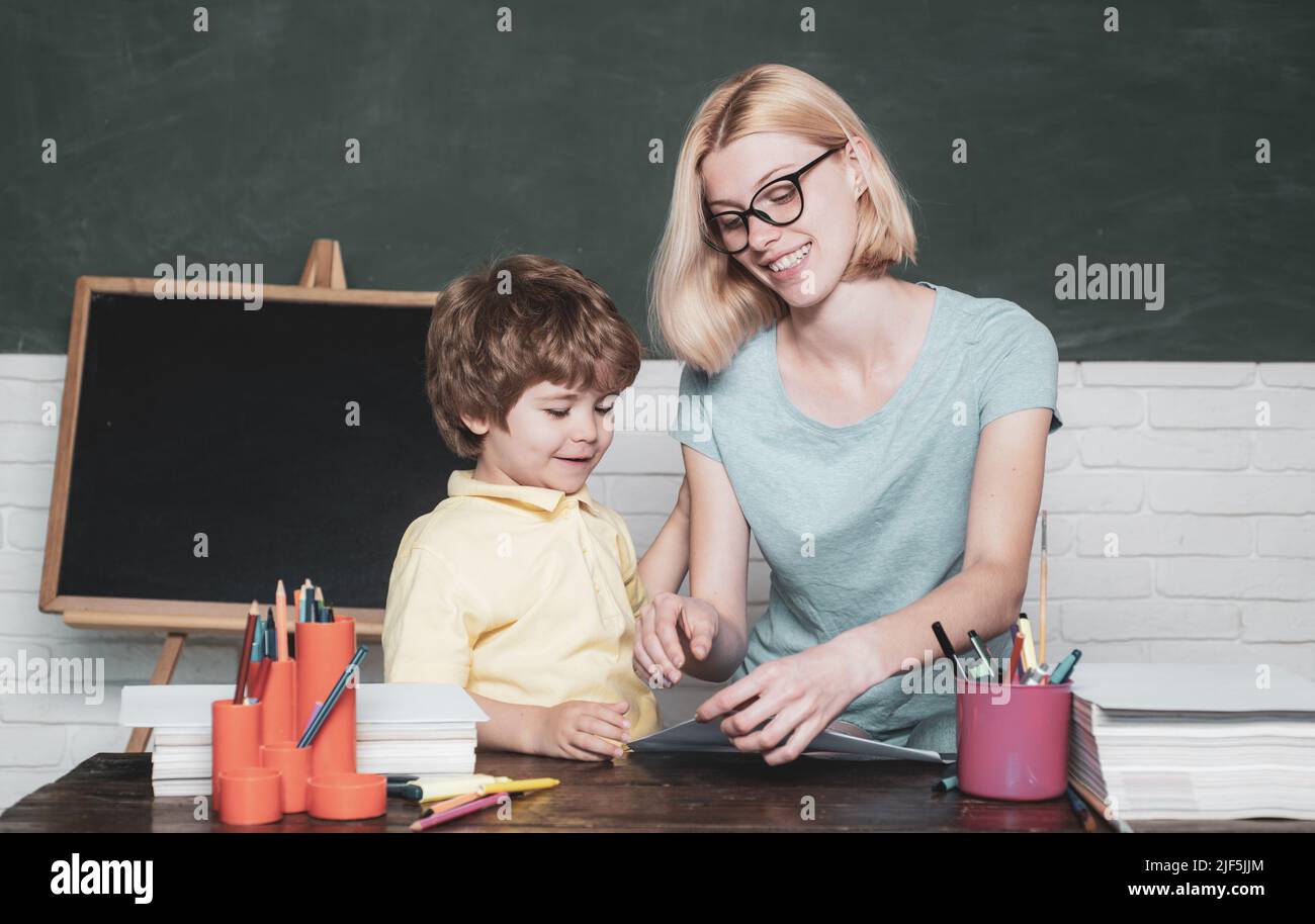 Mother teaching her son in classroom at school. Funny little child and ...