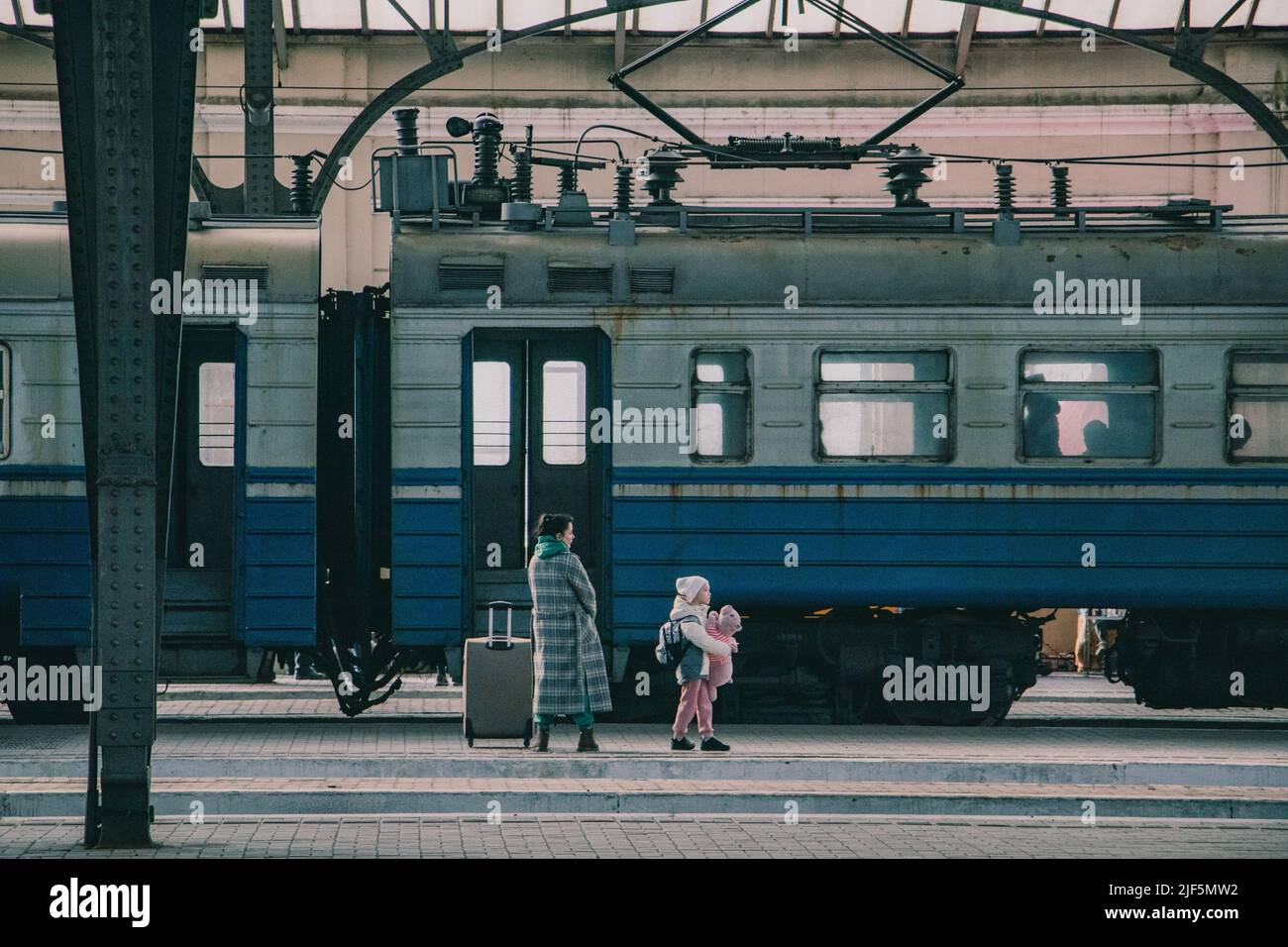 Mother is waiting with her child at the train station to get on the ...