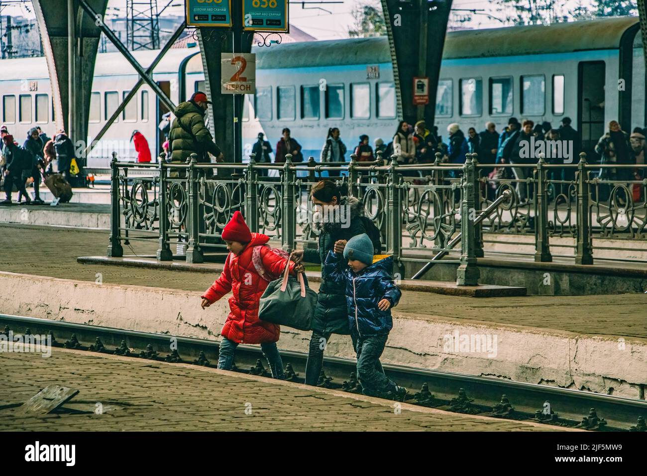 Mother is crossing the platform with her two children. The train ...