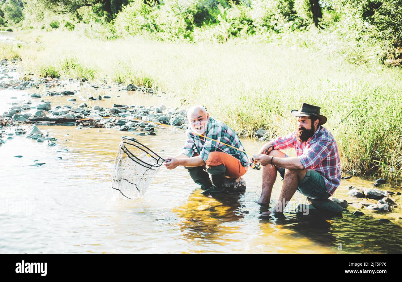 Fishing team. Brutal men sitting near river water. Carry on fishing ...