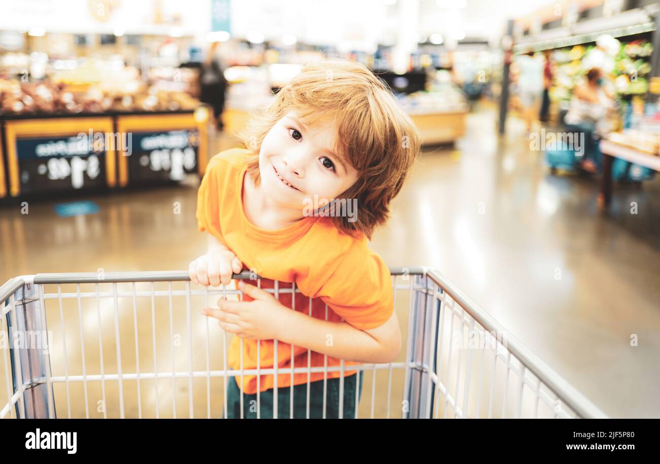 Funny customer boy child holdind trolley, shopping at supermarket ...