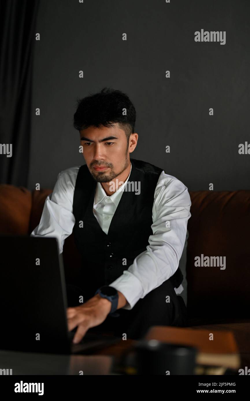 Smart millennial Asian businessman focused working on his project ...