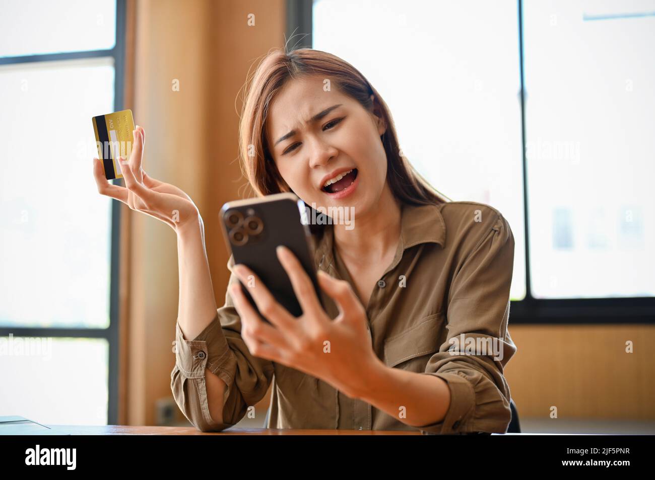 Angry and unhappy young Asian woman having a trouble with online ...