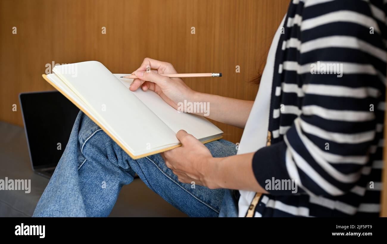 A young female college student writing something on notebook, doing ...