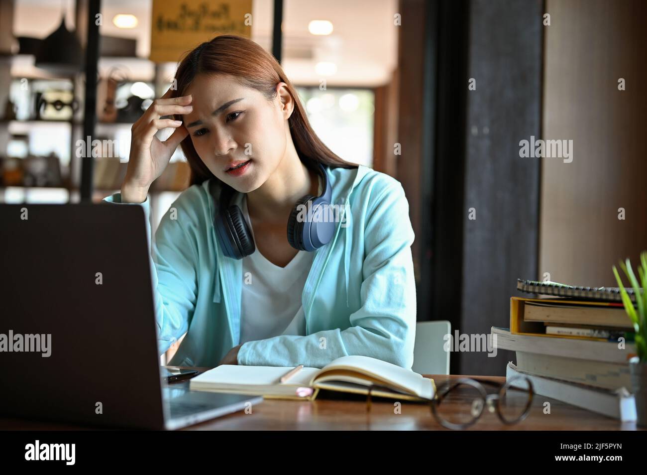 Stressed young Asian female college student in the library, having a ...