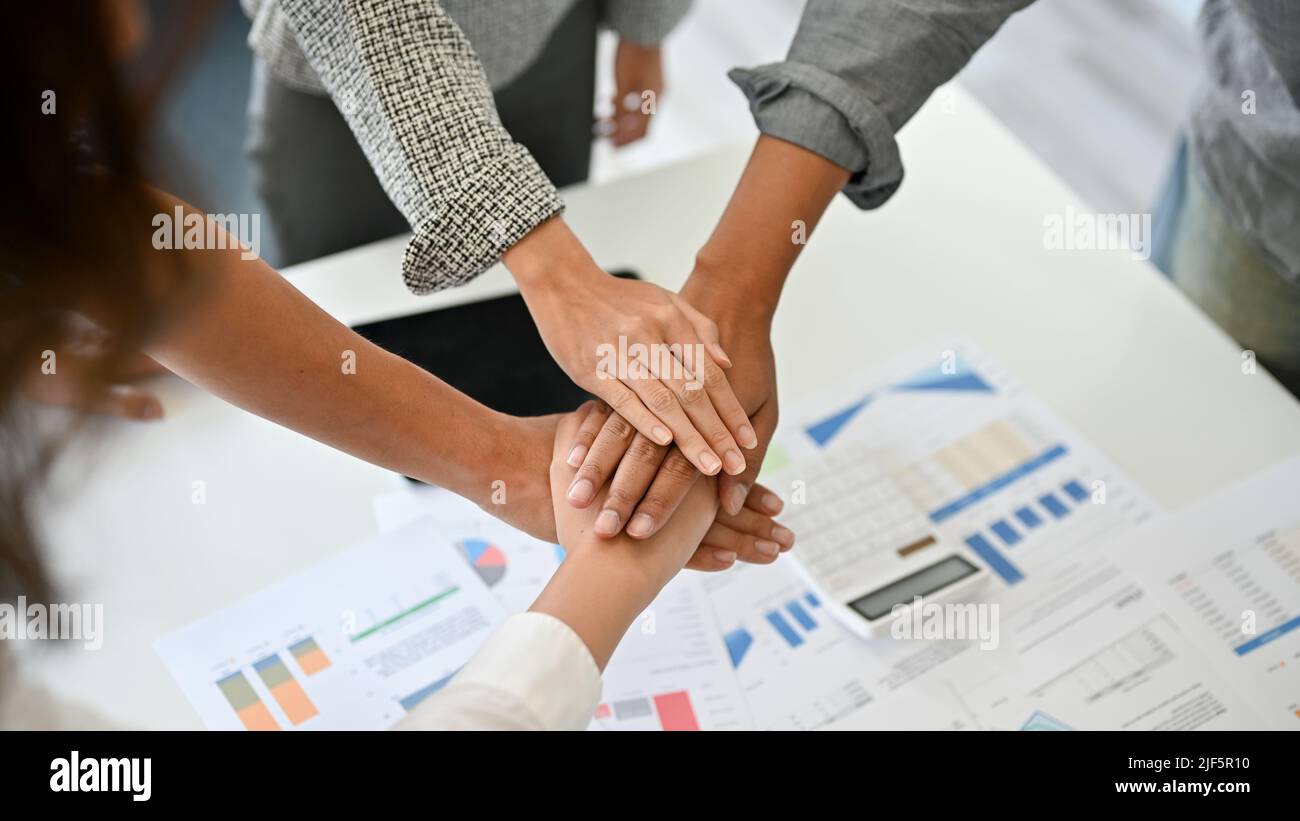 A business group putting their hands together over the meeting table. Unity business teamwork ...