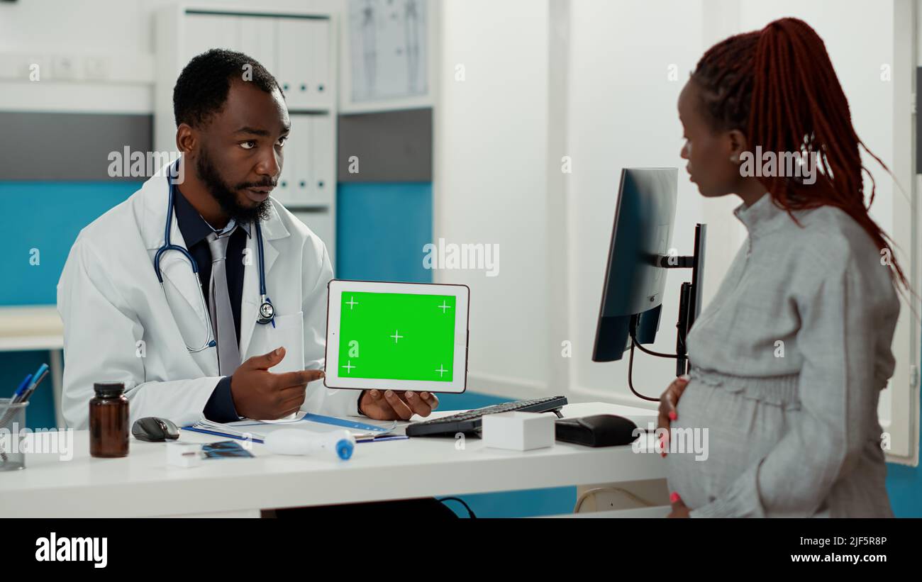 Health specialist showing horizontal greenscreen on tablet to patient ...