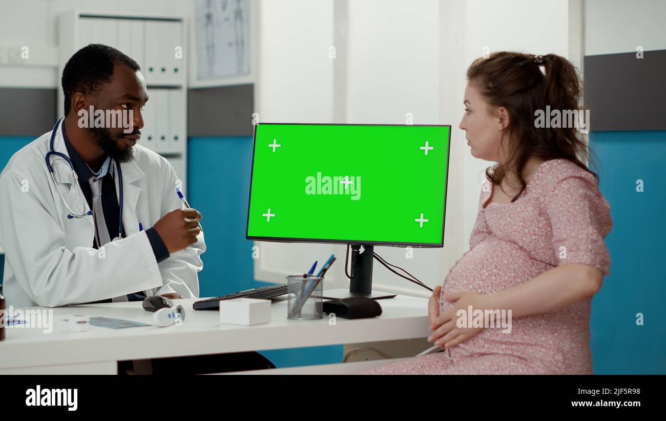 Medical specialist using computer with greenscreen at desk, consulting ...