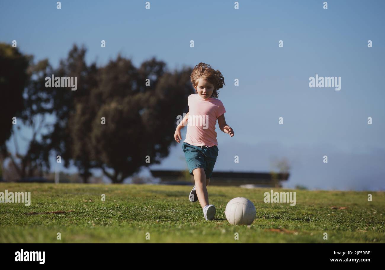Boy child kicking football on the sports field during soccer match ...