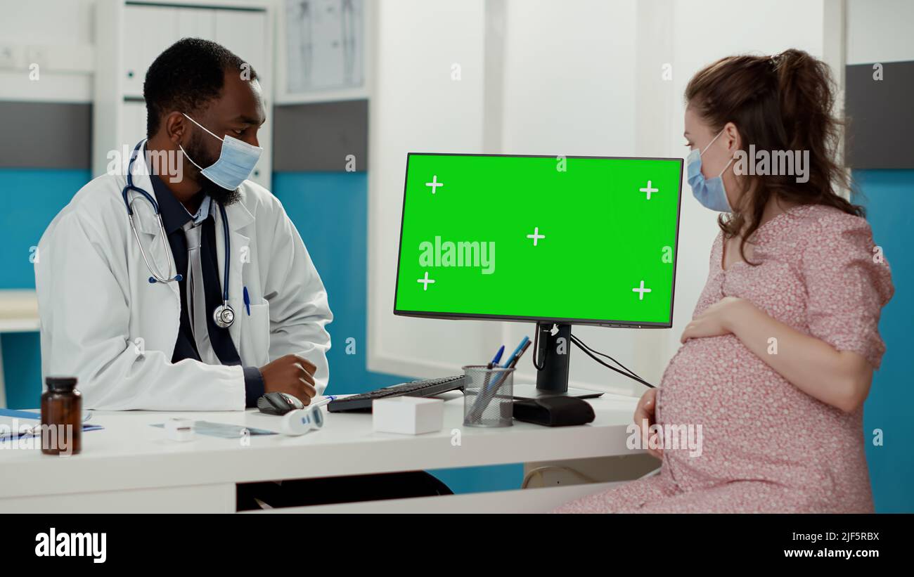 Doctor and patient with pregnancy belly looking at greenscreen on ...