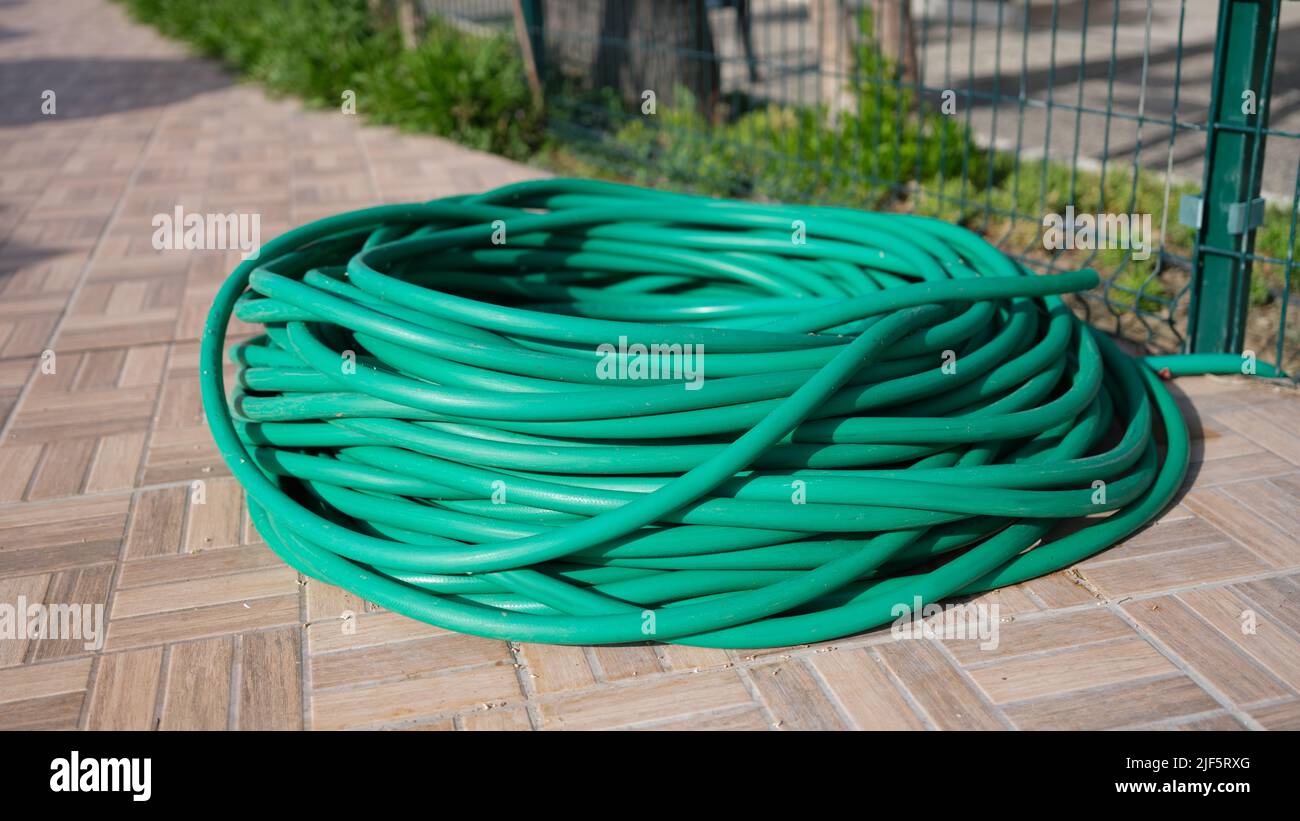 Coiled garden hose lies on ground closeup Stock Photo - Alamy