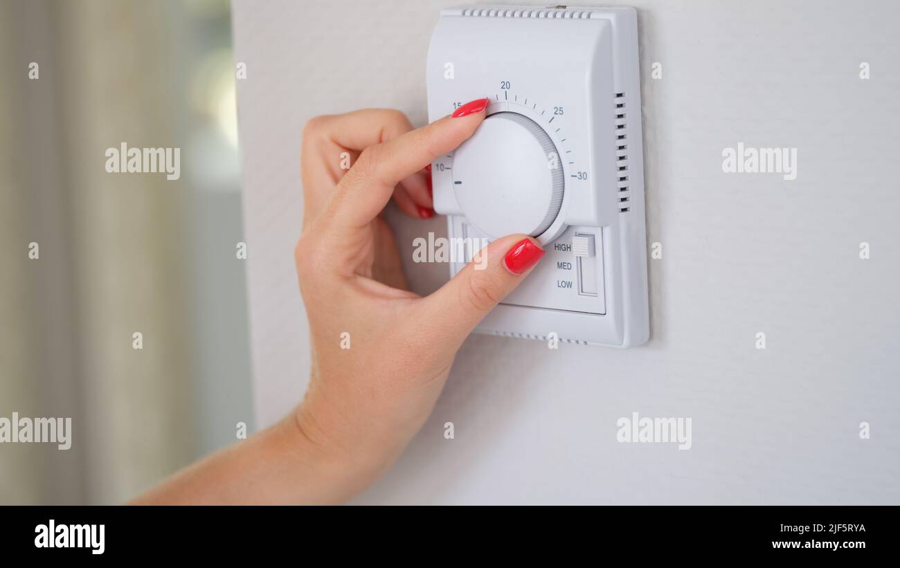Woman's hand regulating the temperature of central heating of house on ...