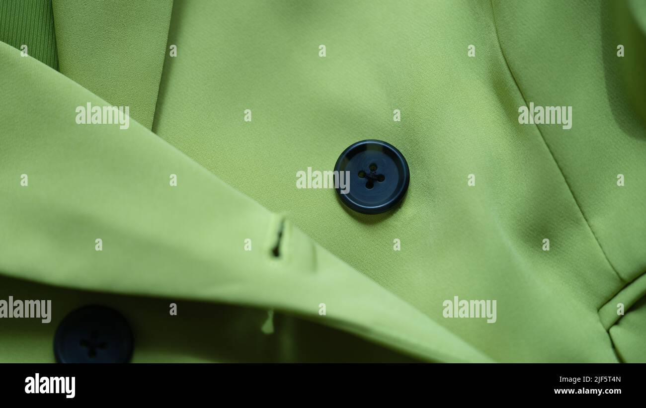 Closeup of green jacket with black button Stock Photo - Alamy
