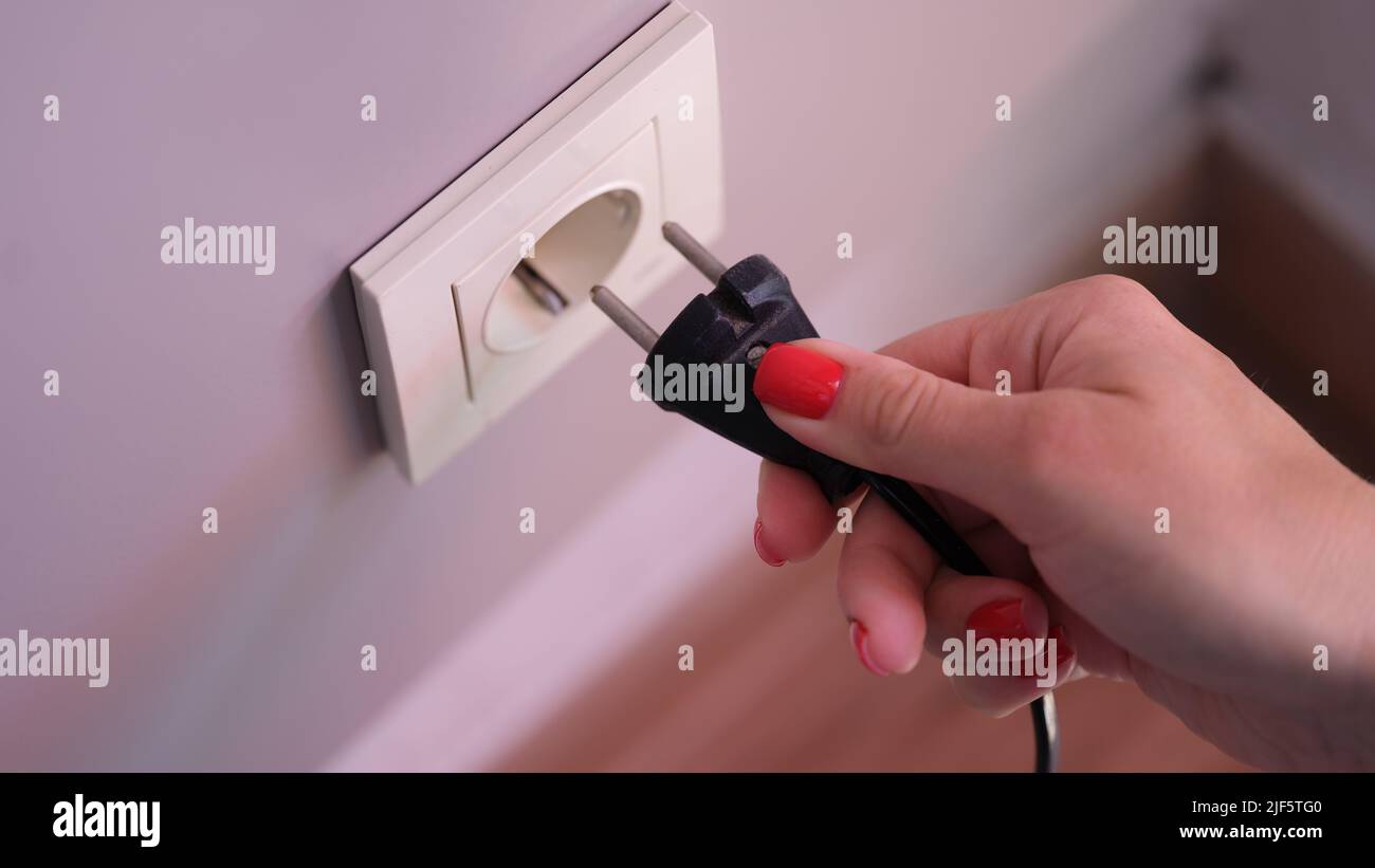 Connecting black electric plug with hand to white plastic socket on ...