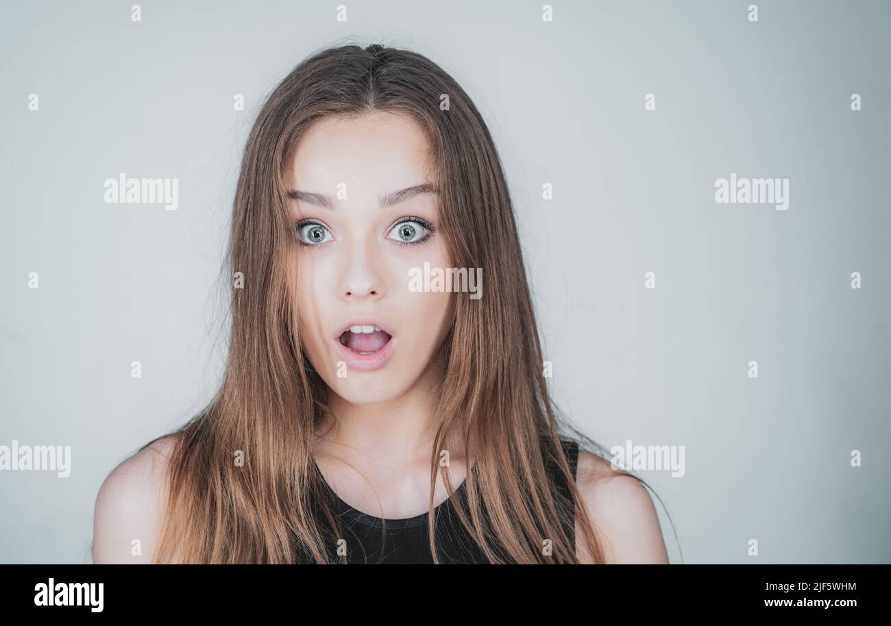 Young attractive girl with surprise curiosity emotion looking at camera ...