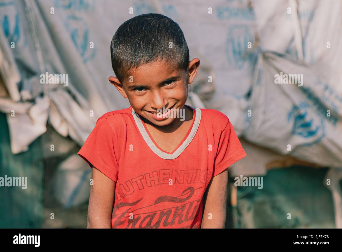 Syrian boy is smiling into the camera. This informal refugee camp with ...