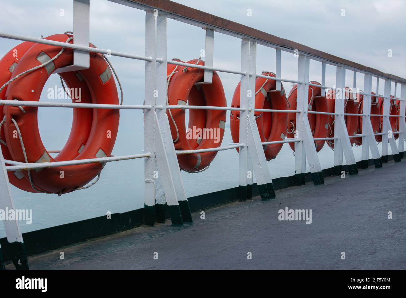 Lifebuoys hang on board a sea ferry floating on the waves Stock Photo ...