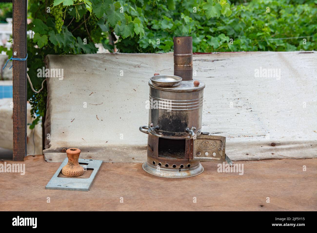 A smoky Turkish samovar with an open stove door stands in the courtyard ...