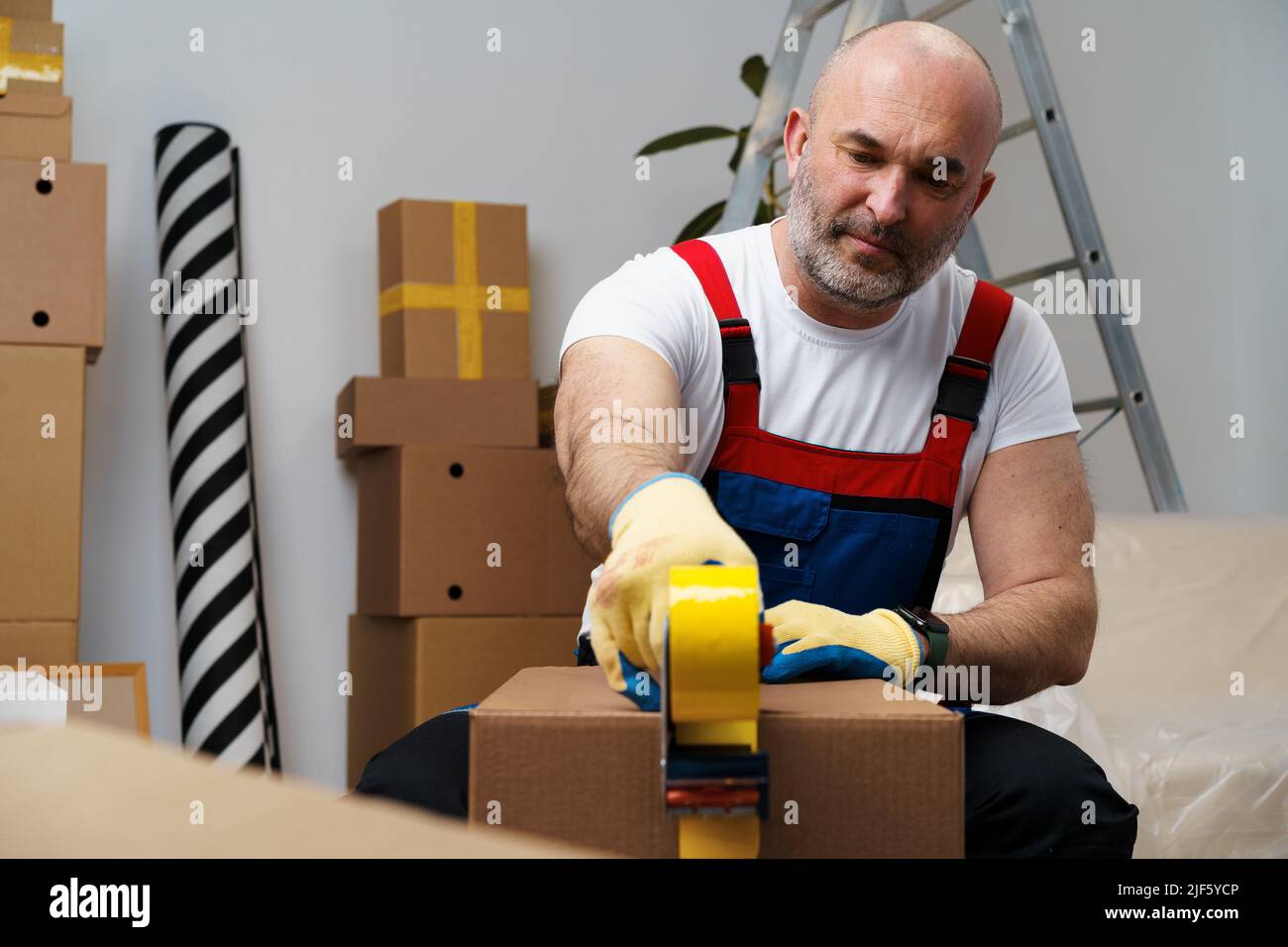 Man mover in uniform packing boxes with scotch tape Stock Photo - Alamy