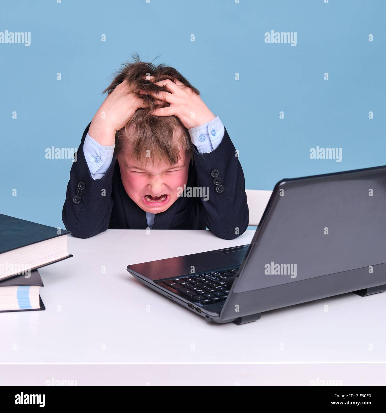A scared boy in a school suit on distance learning, copy space on a ...