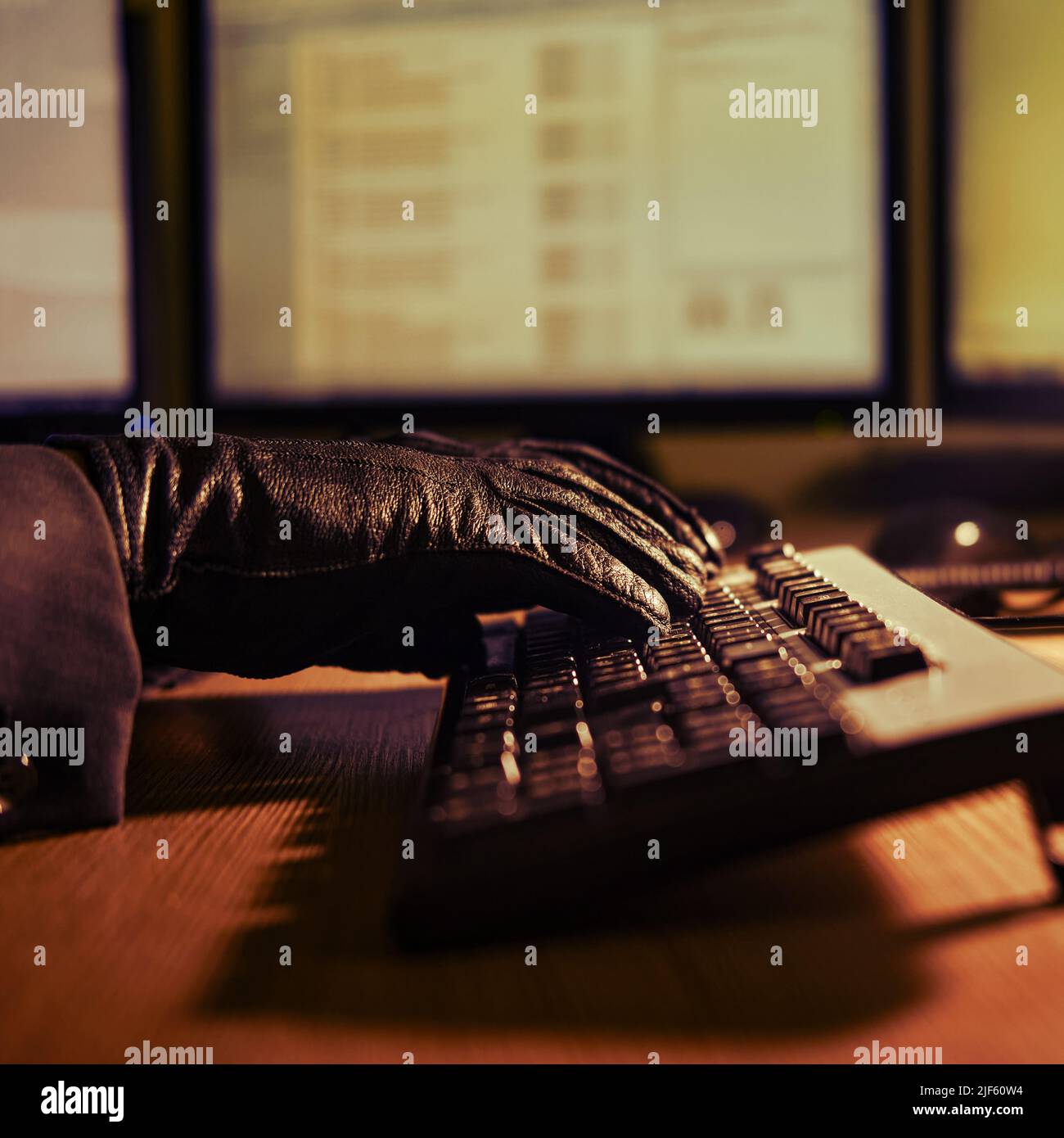 Man attacker hacker in black gloves on his hands working on a computer ...
