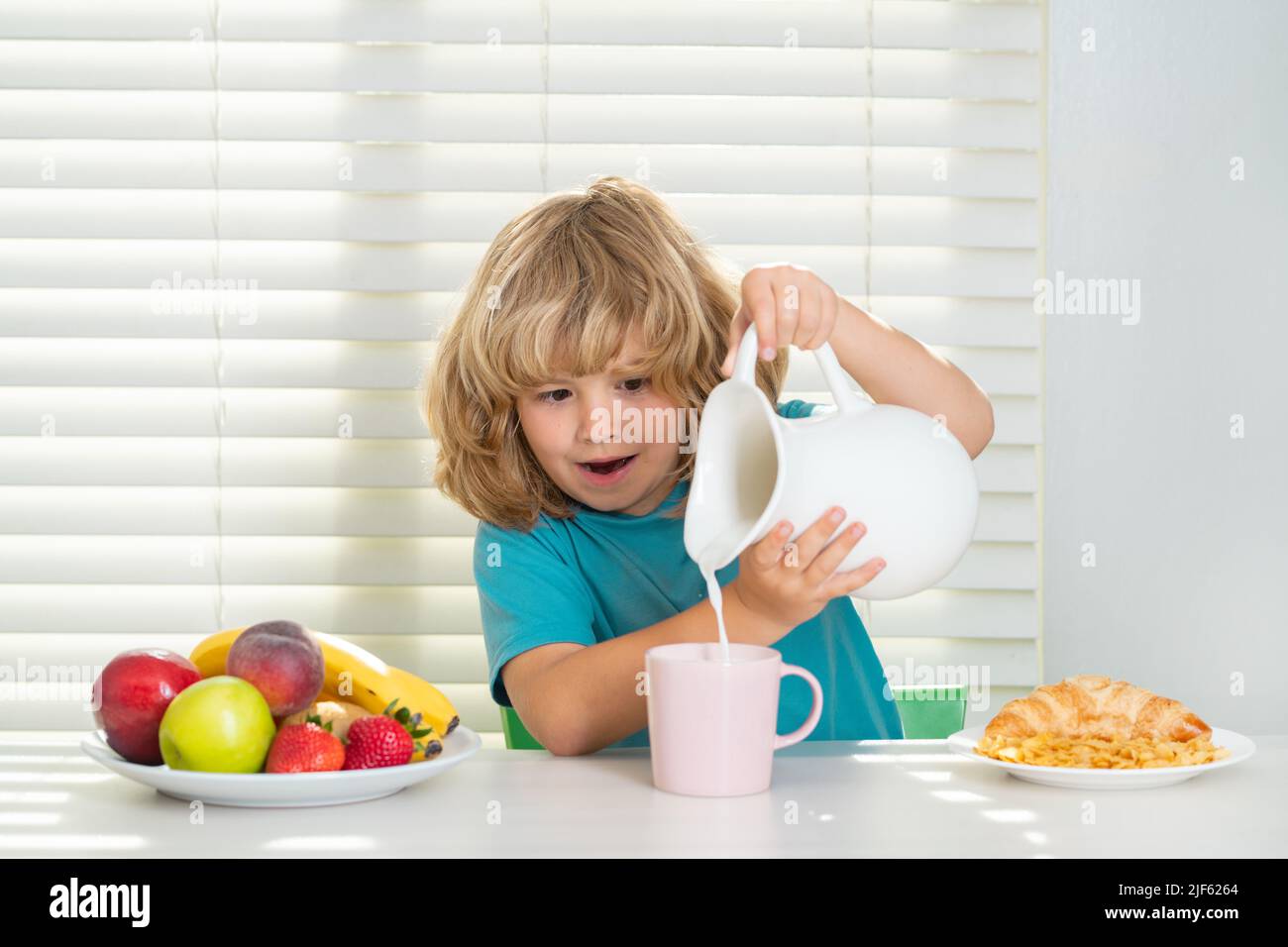 Kid pouring whole cows milk. Kid preteen boy in the kitchen at the ...