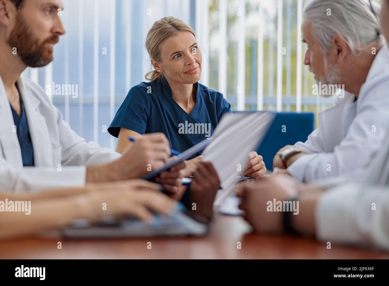 Group of doctors sitting at meeting table in conference room during ...
