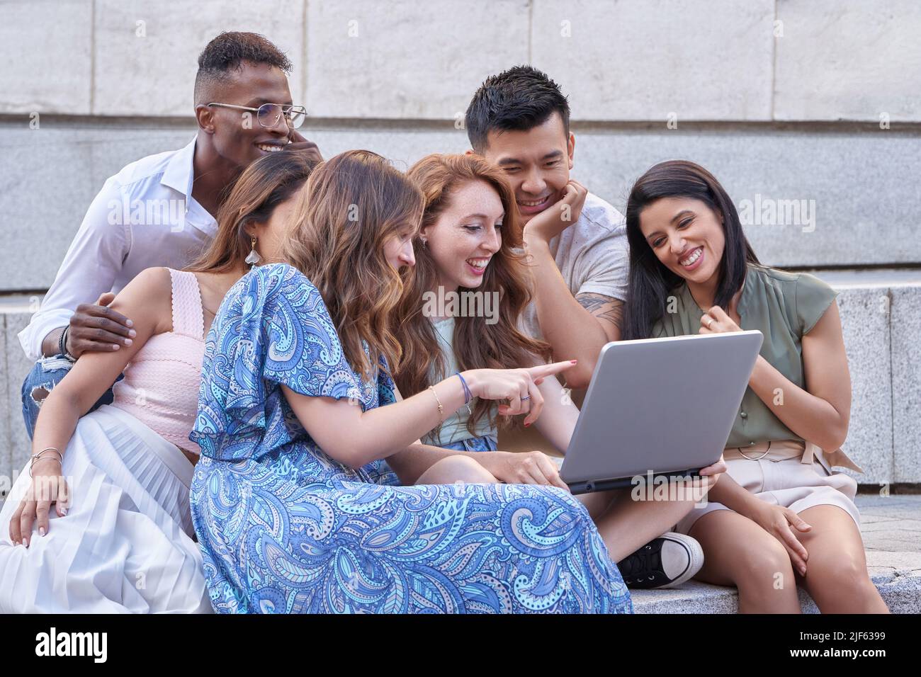 Group of multi-ethnic people using laptop together while sitting on ...