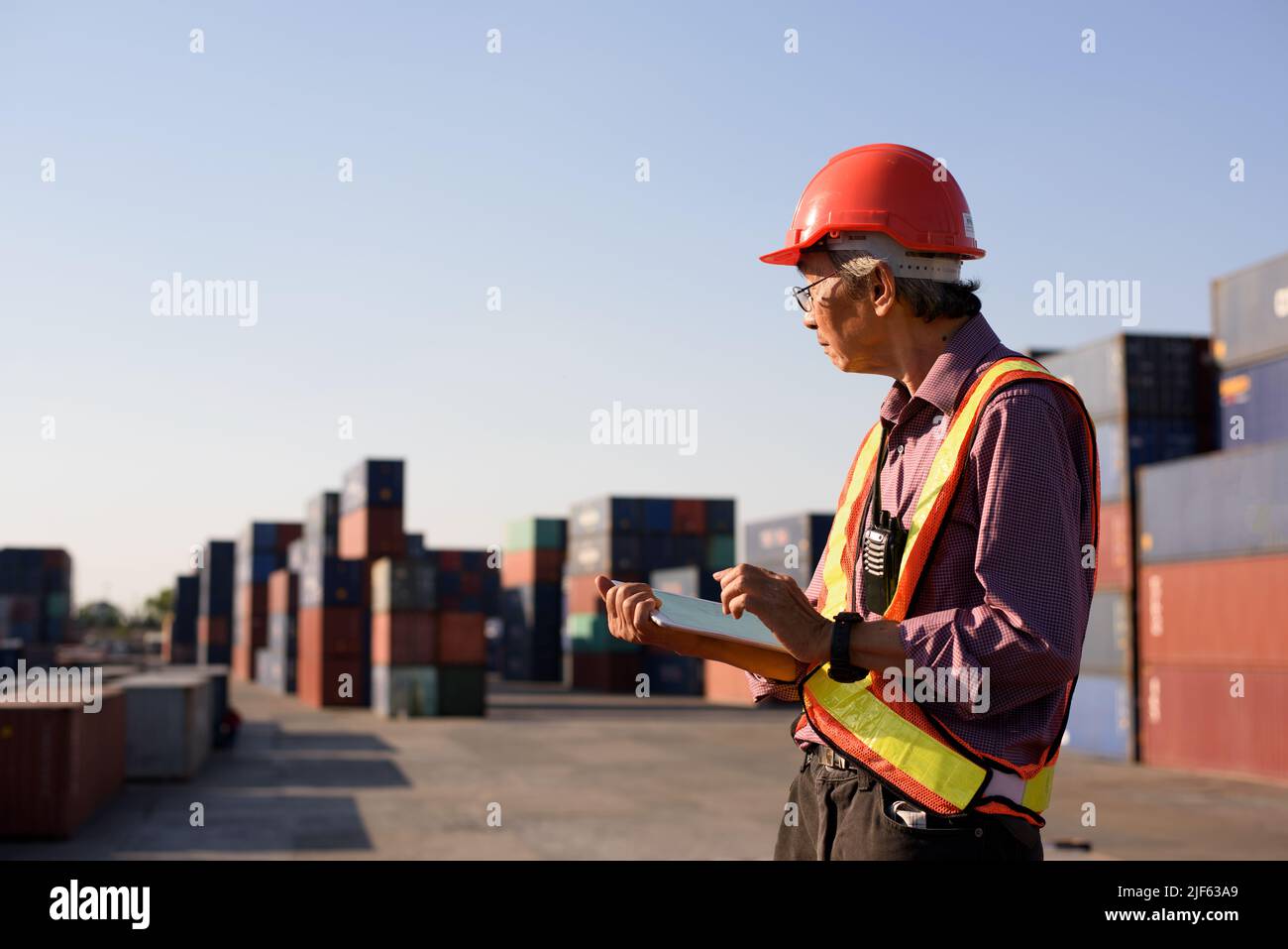 A senior elderly Asian worker engineer wearing safety vest and helmet ...