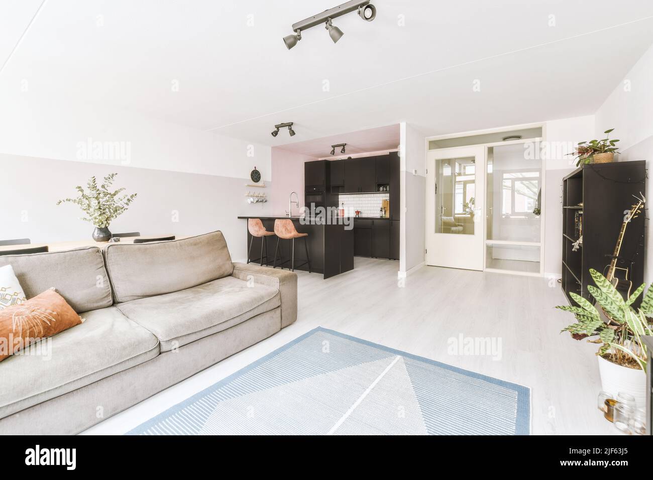 Simple interior of light living room with gray sofa in front of TV and ...