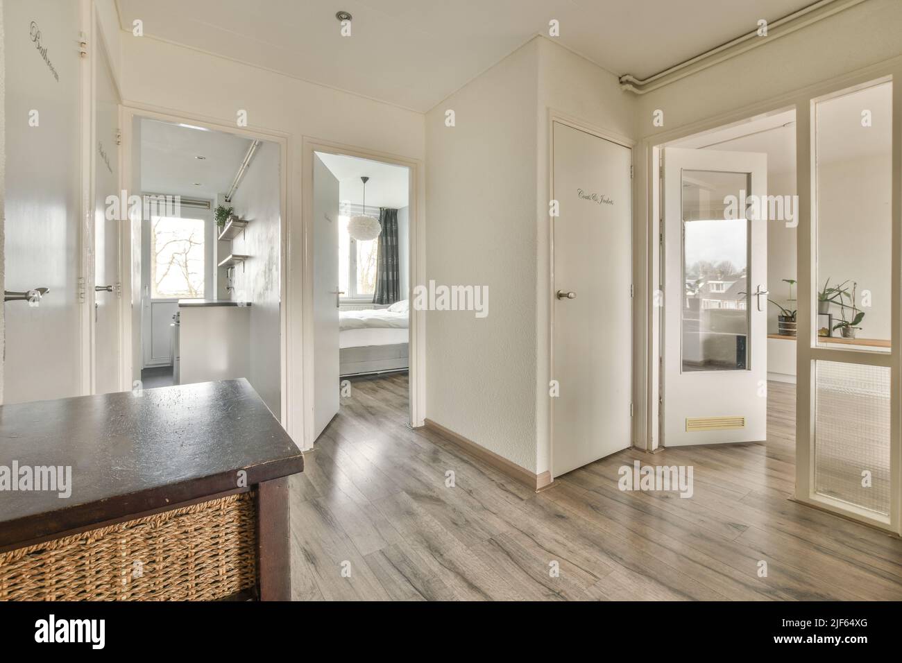 Corridor with white walls and doors leading to spacious room with ...