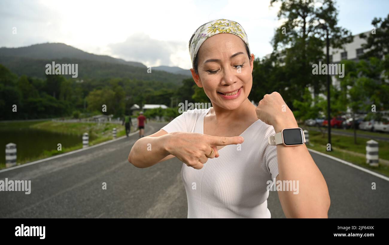 Healthy middle aged woman pointing at her smartwatch. Fitness, sport ...