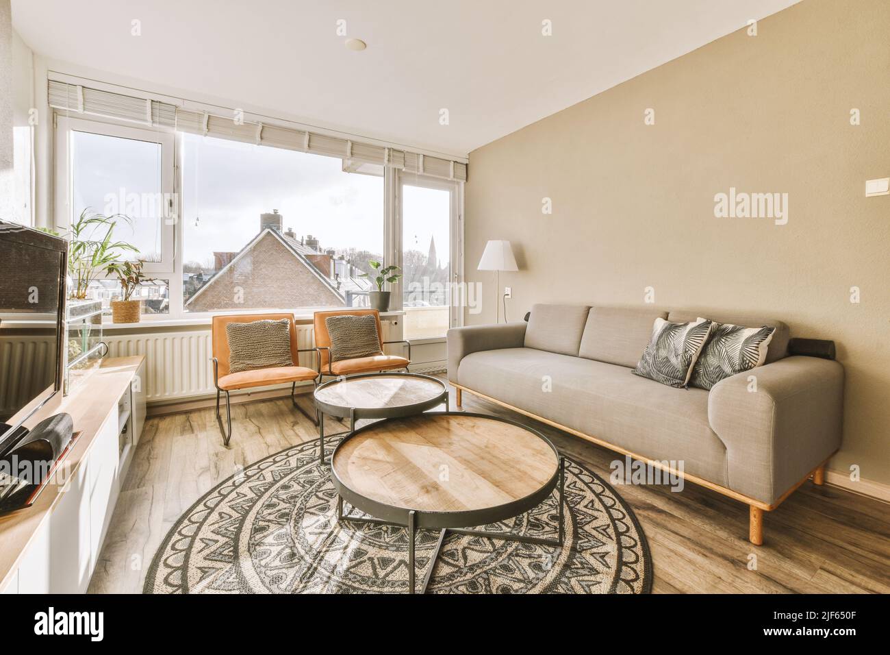 Simple interior of light living room with gray sofa in front of TV and ...