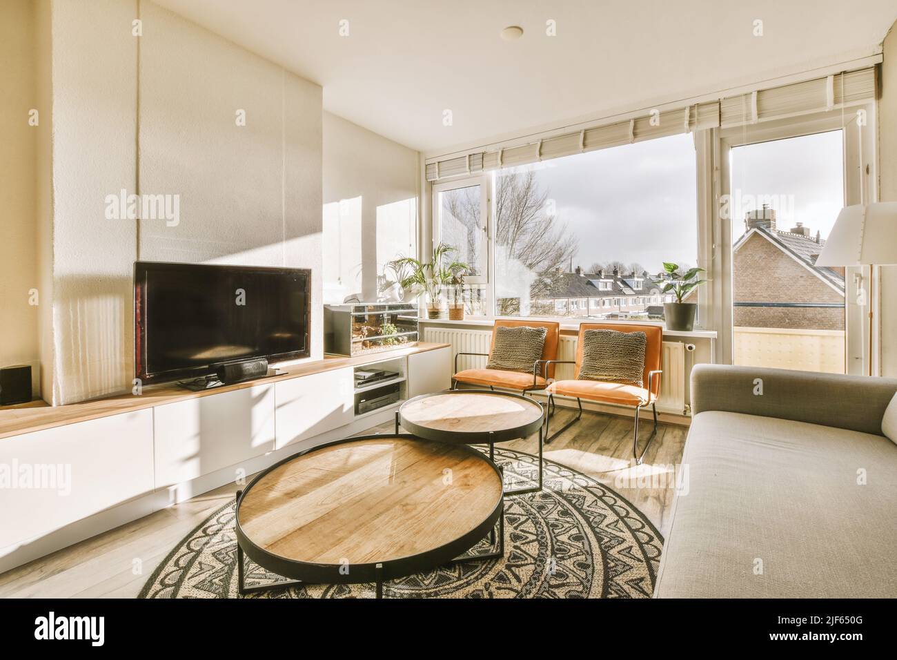 Simple interior of light living room with gray sofa in front of TV and ...