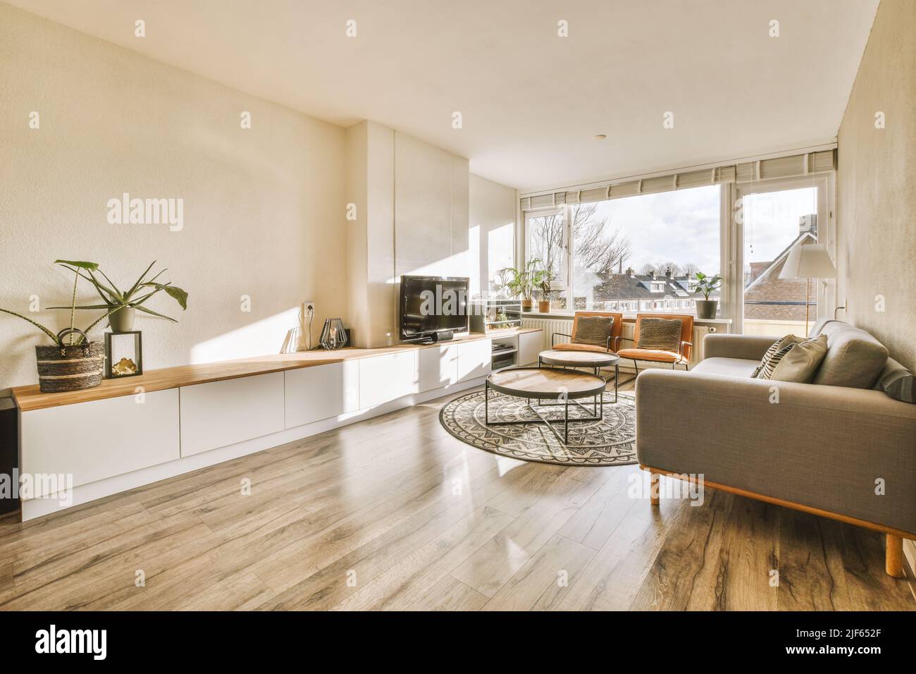 Simple interior of light living room with gray sofa in front of TV and ...