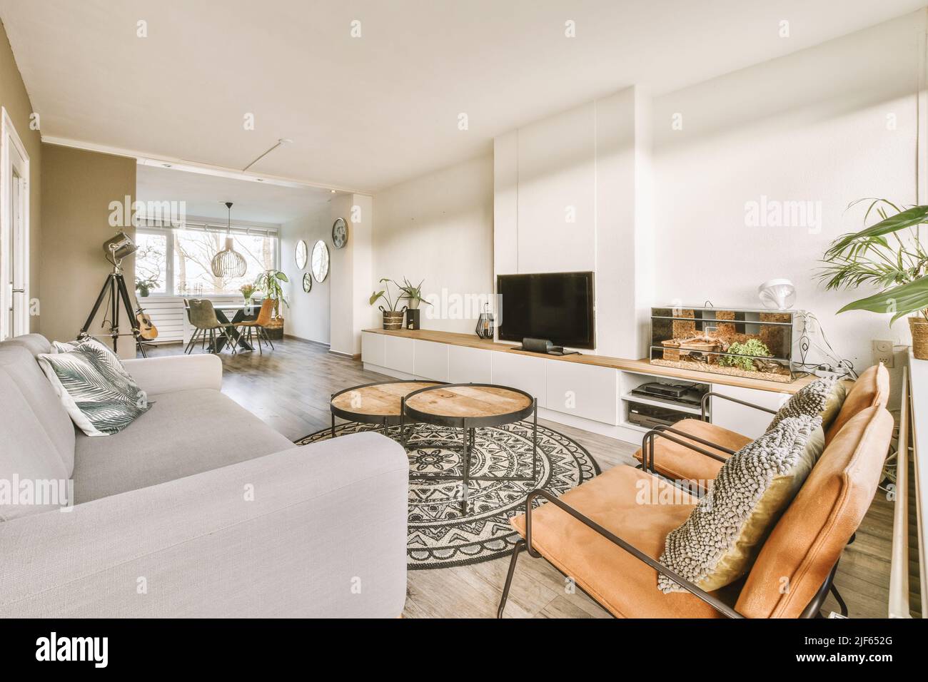 Simple interior of light living room with gray sofa in front of TV and ...