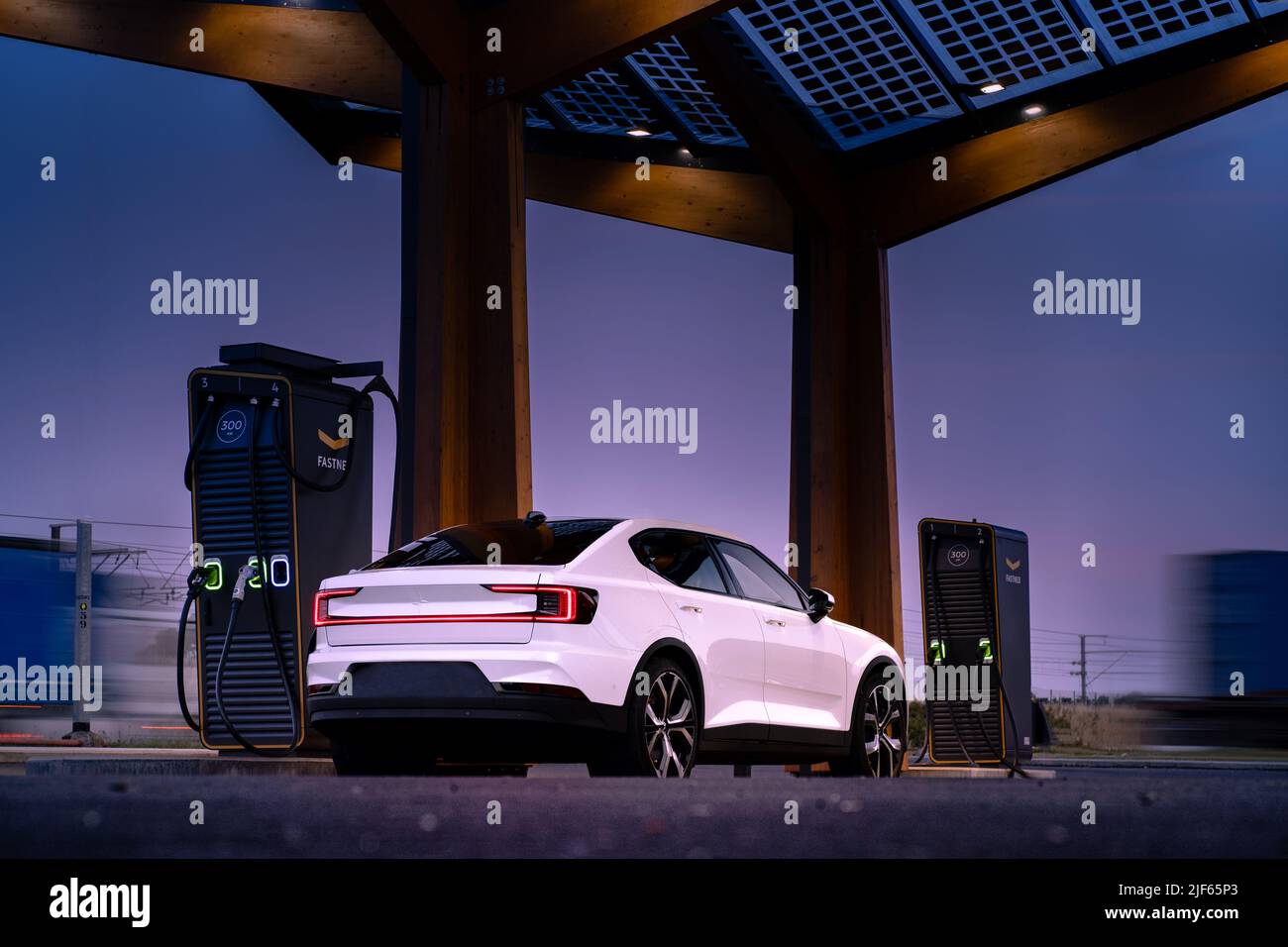 A low-angle shot of snow-white Volvo Polestar 2 charging during blue ...