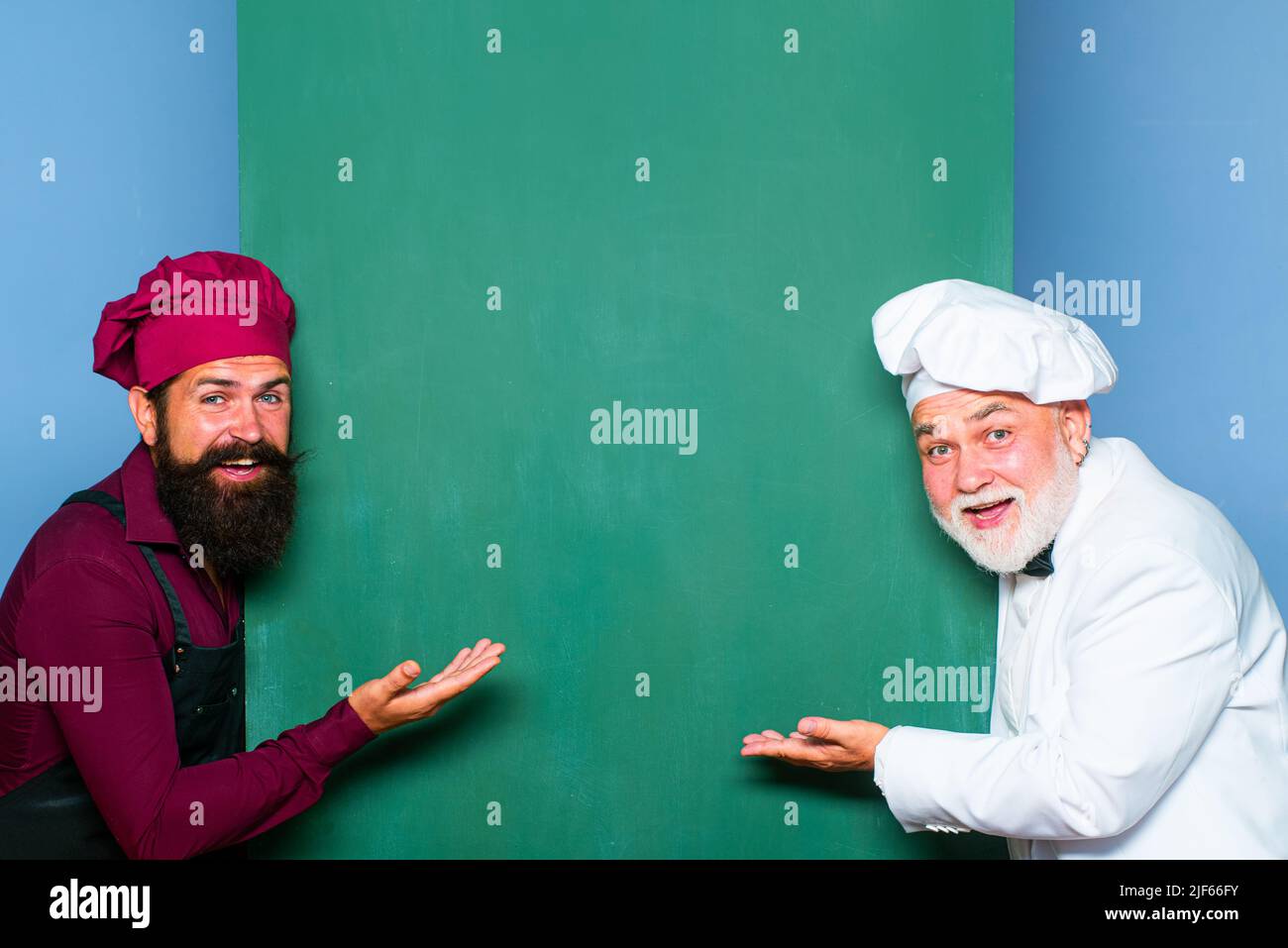 Chef men in cook hat pointing spoon on blank board menu. Chef, cook or ...