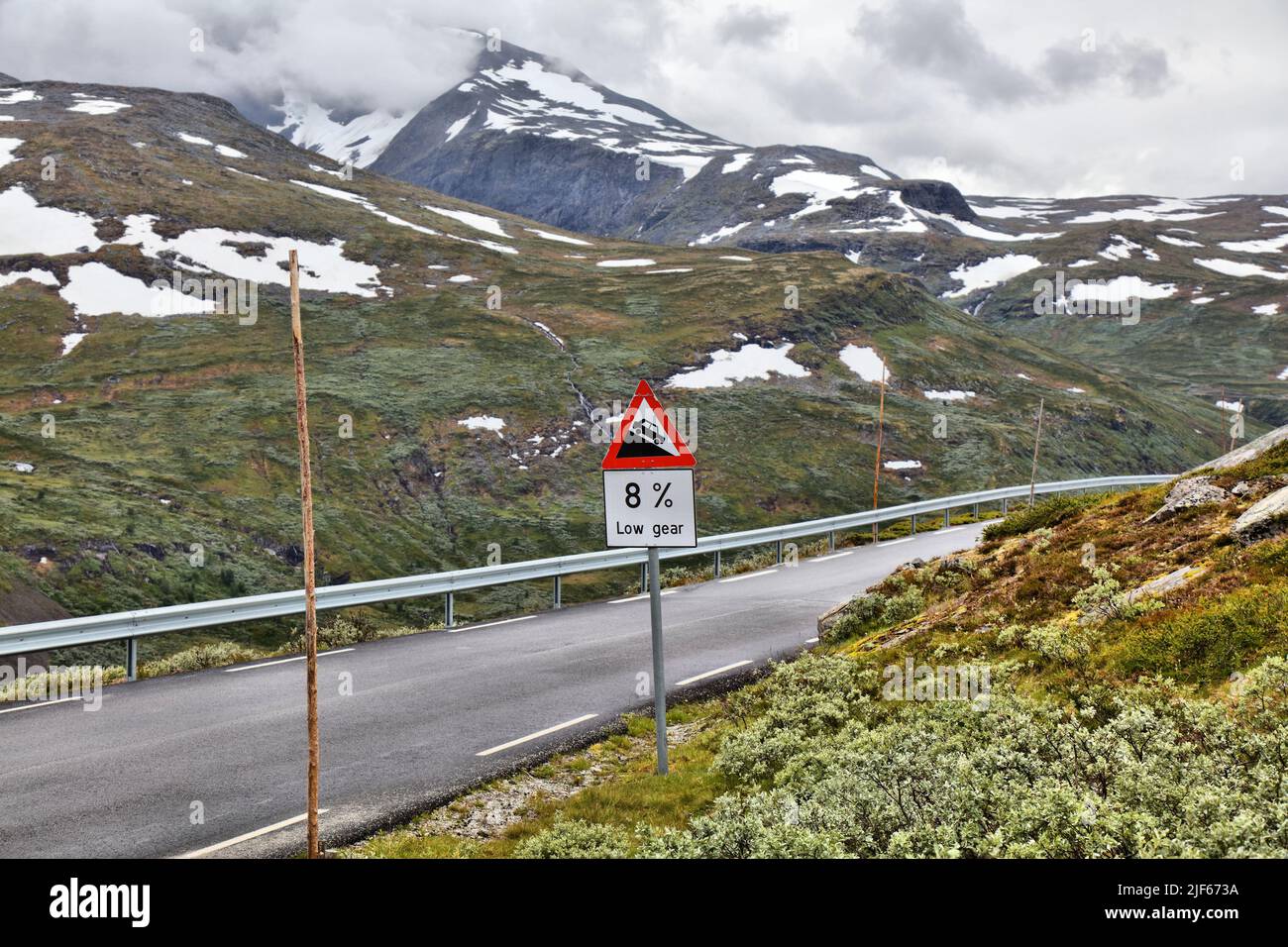 Low gear warning on a steep mountain road in Norway. Wooden snor marker ...