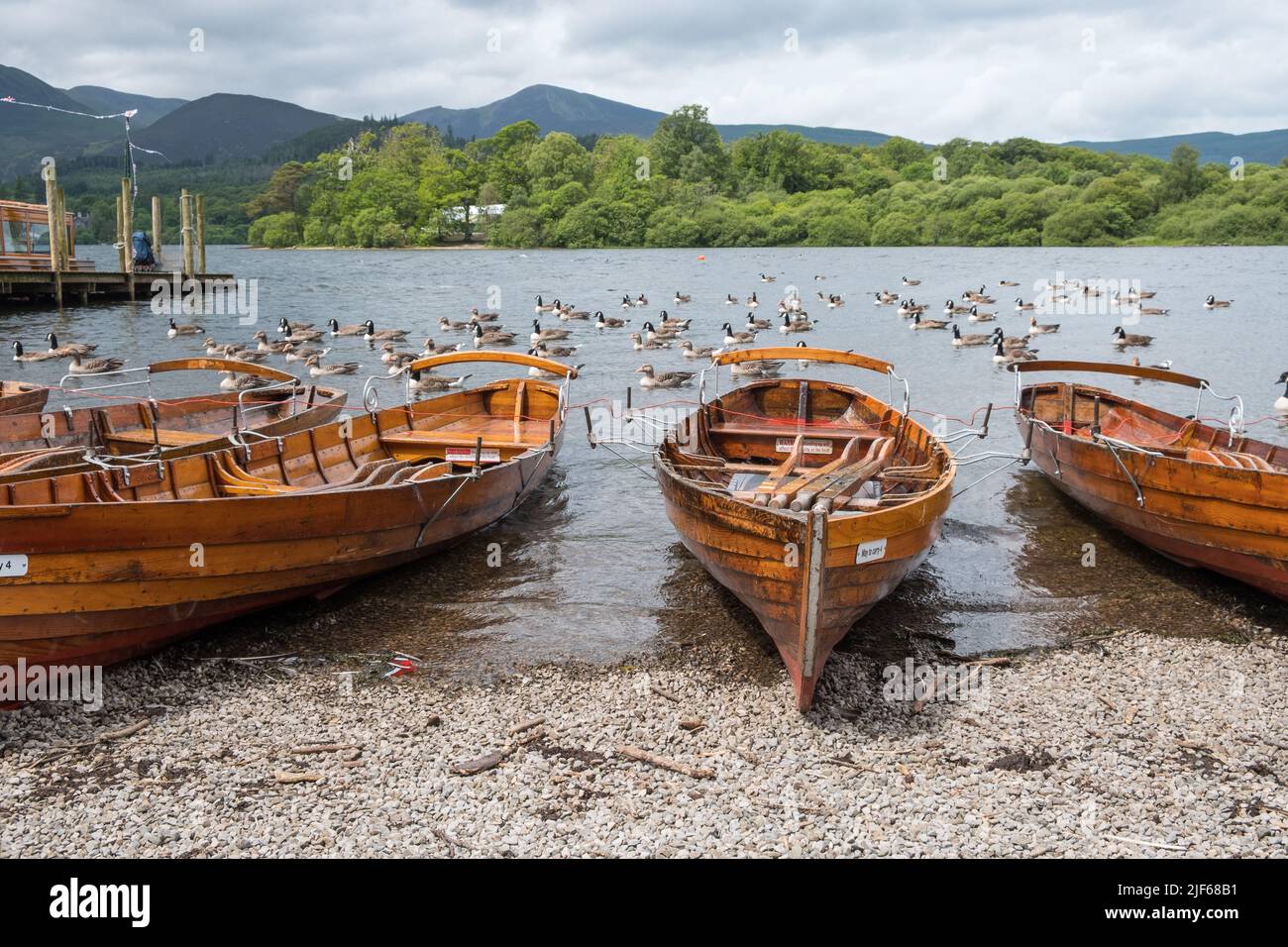 Wooden rowing boats for hire line the shore of Derwent Water at Keswick ...