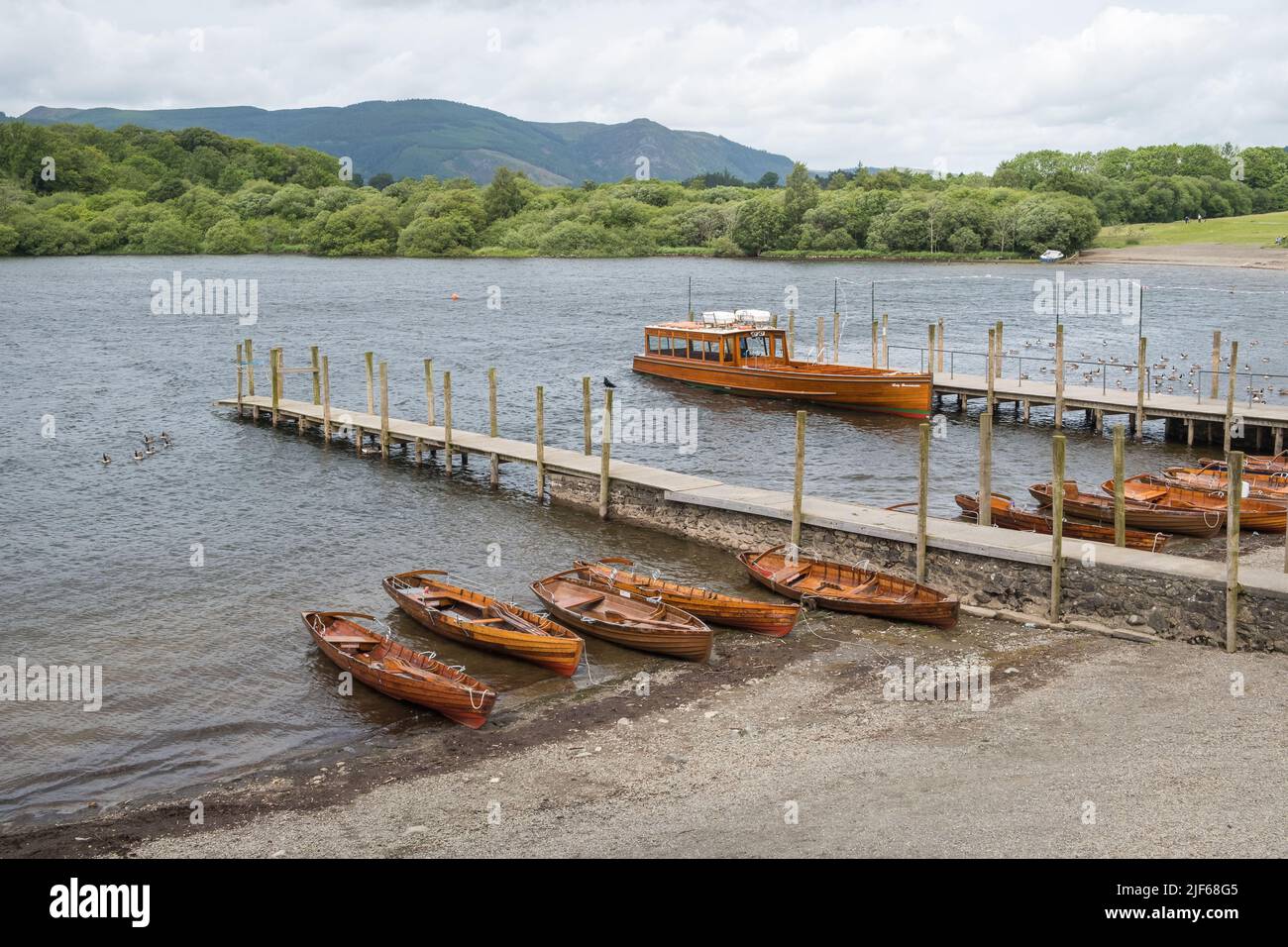 Wooden rowing boats for hire line the shore of Derwent Water at Keswick ...