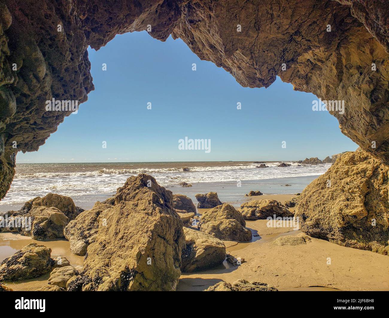 A scenic view of ocean waves crushing against a sandy beach seen from a ...