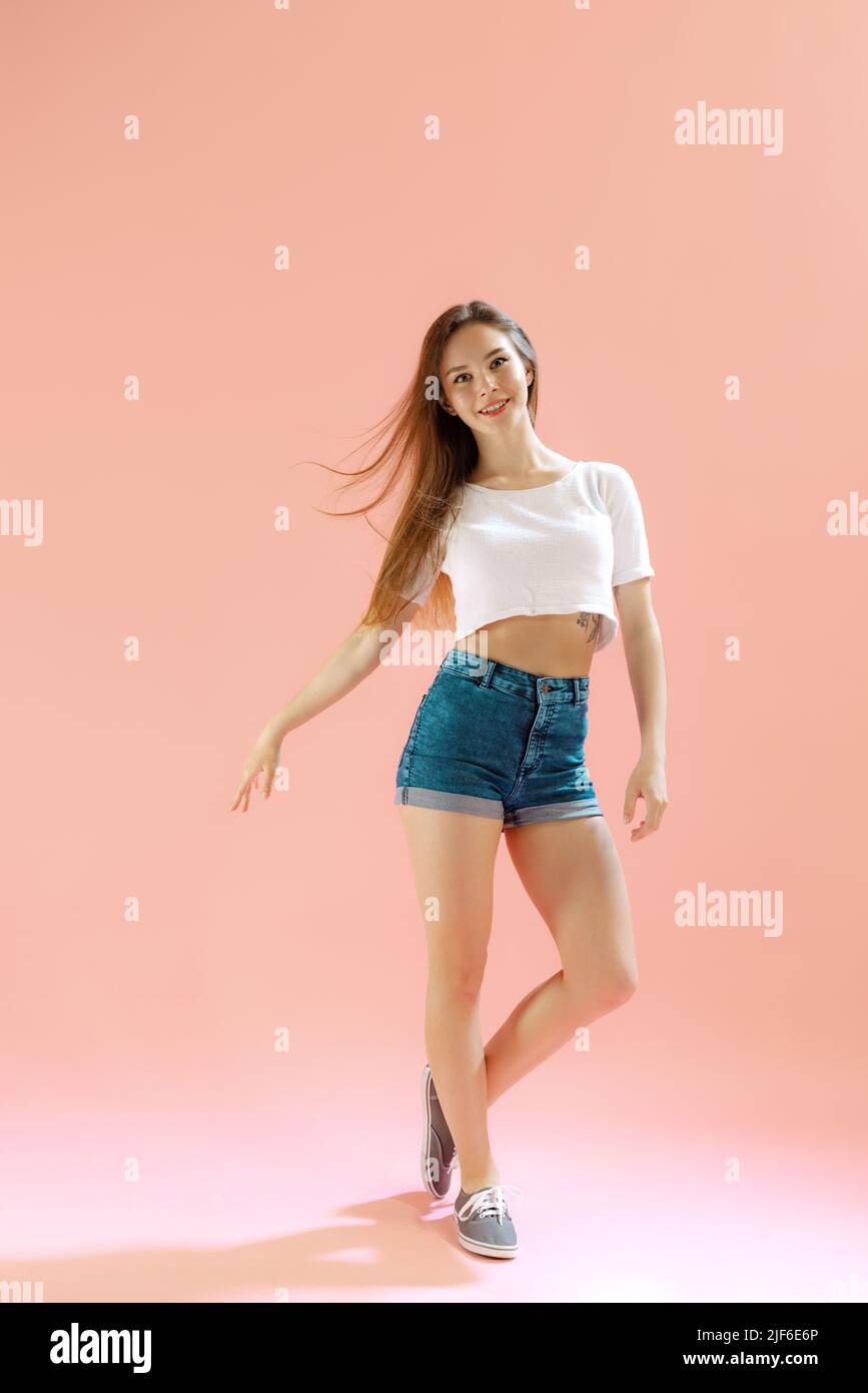Full-length portrait of young stylish girl in shorts and T-shirt posing ...